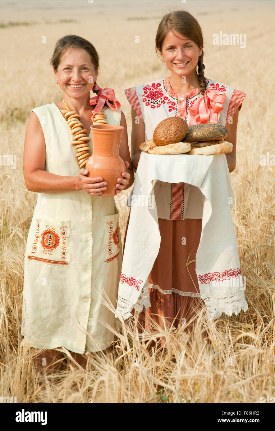 Women in traditional clothes with bread at cereals field Stock Photo ...