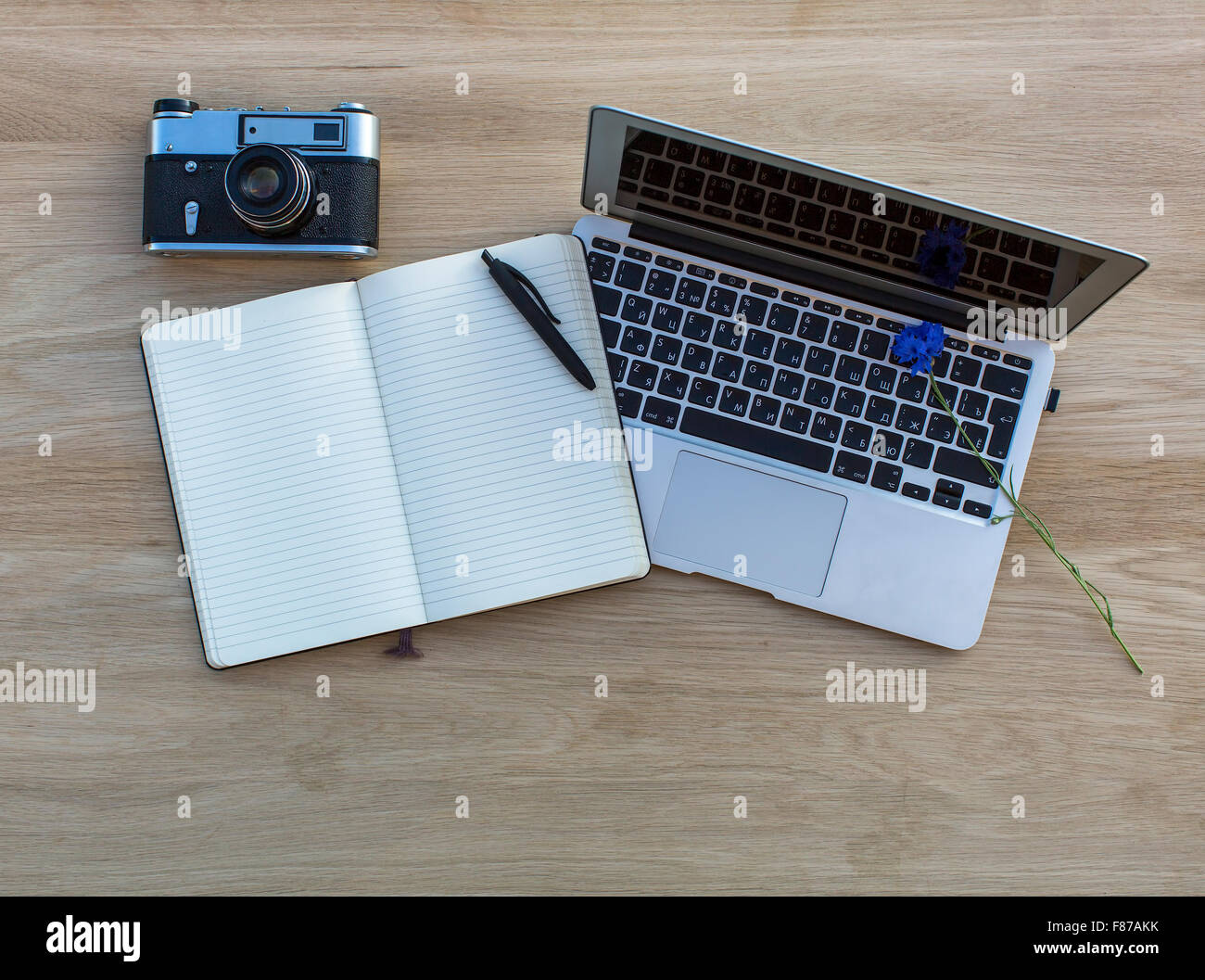 Laptop, opened notepad laptop, and vintage film camera lying on a ...