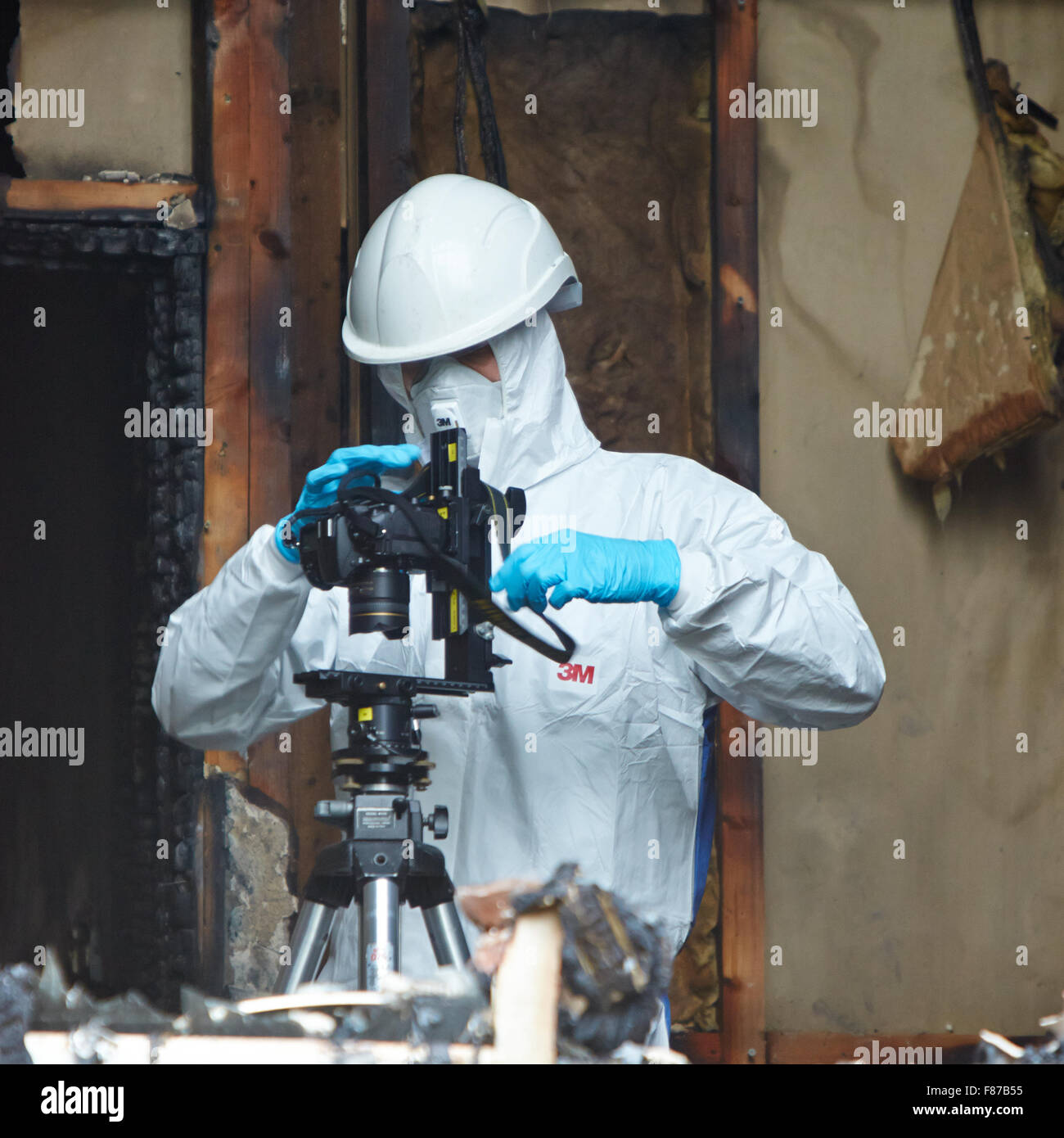 A police forensic investigator examines the scene of a fatal house fire ...