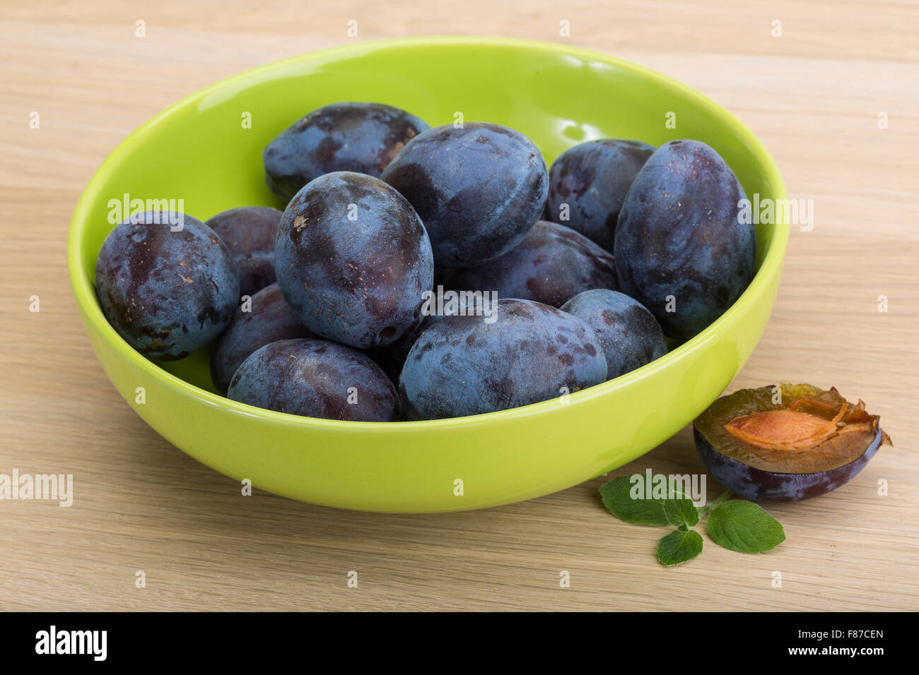 Fresh ripe prunes in the bowl on wooden background Stock Photo - Alamy