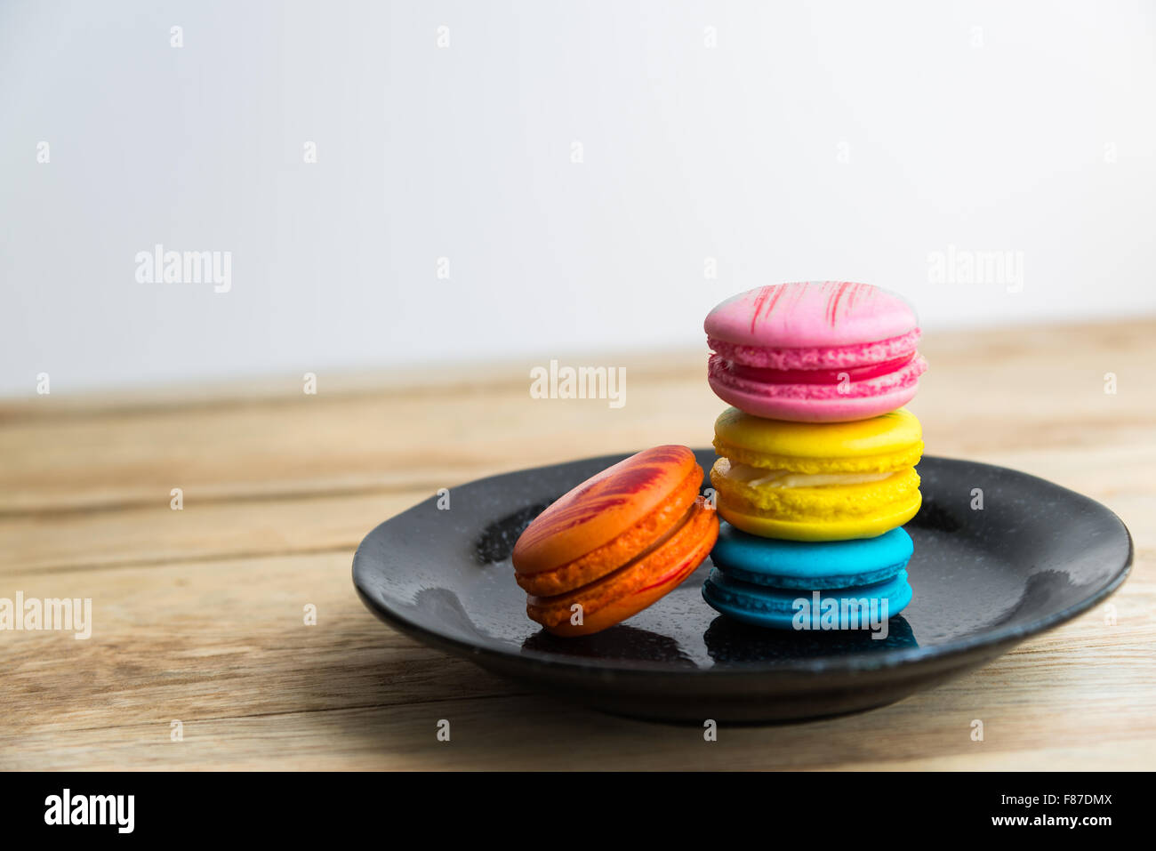Colorful macaroon in black dish on wooden floor Stock Photo - Alamy