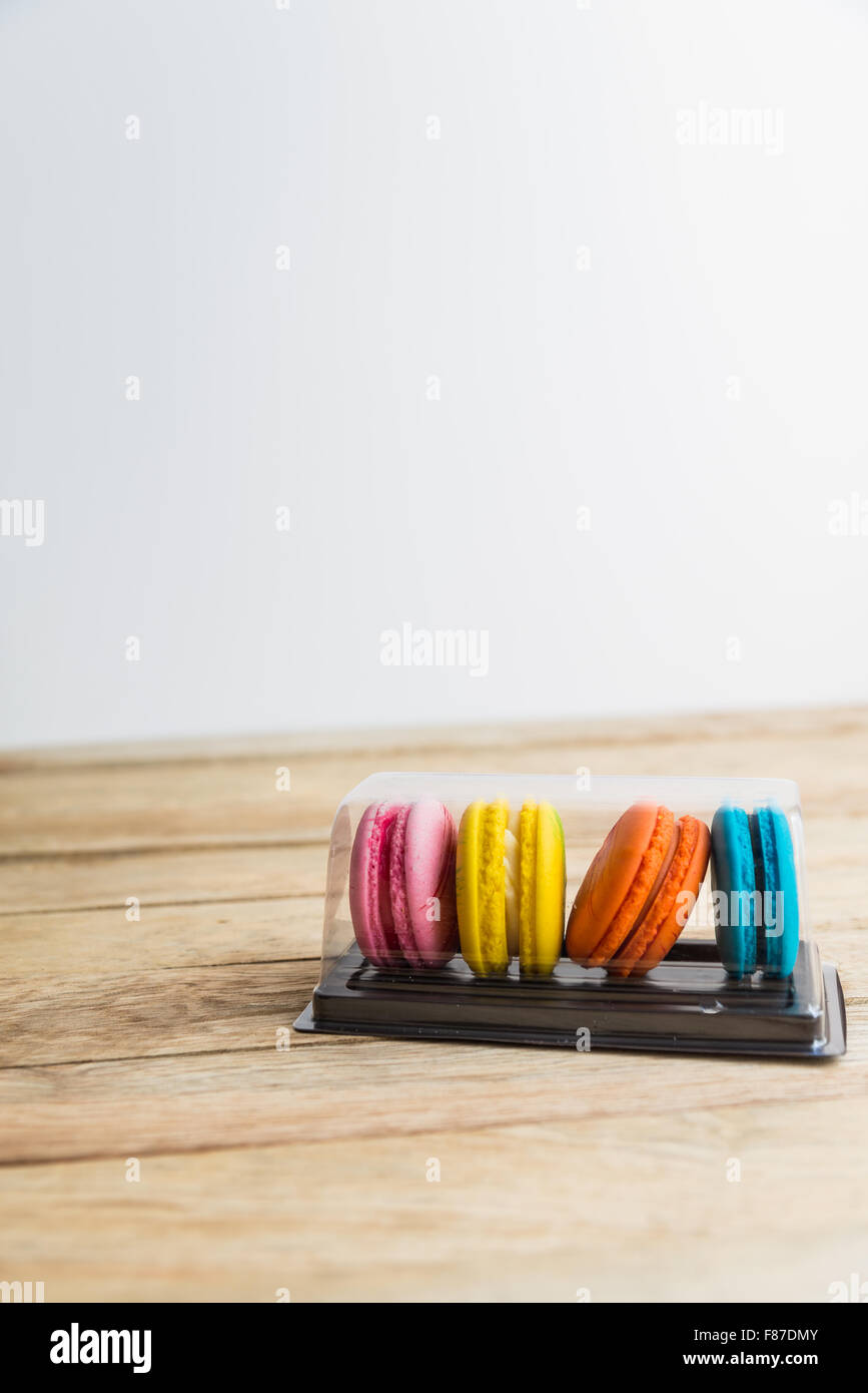 Colorful macaroon in plastic box on wooden floor Stock Photo - Alamy