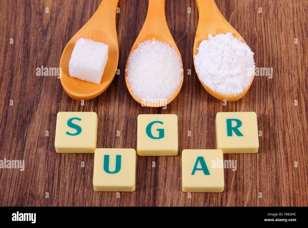 Sugar cube, granulated and powdered sugar on wooden spoons with text ...