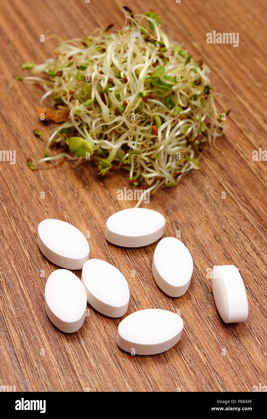 Tablets supplements with alfalfa and radish sprouts on wooden surface ...
