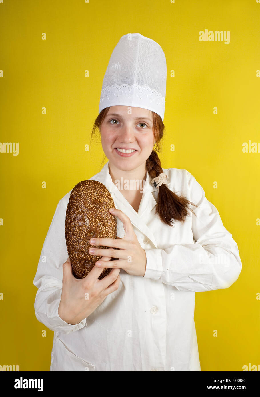 female baker is showing fresh bread over yellow Stock Photo - Alamy