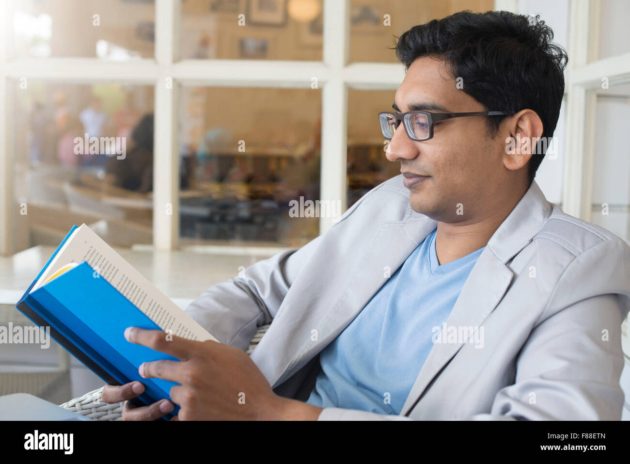 young indian male reading book on cafe Stock Photo - Alamy