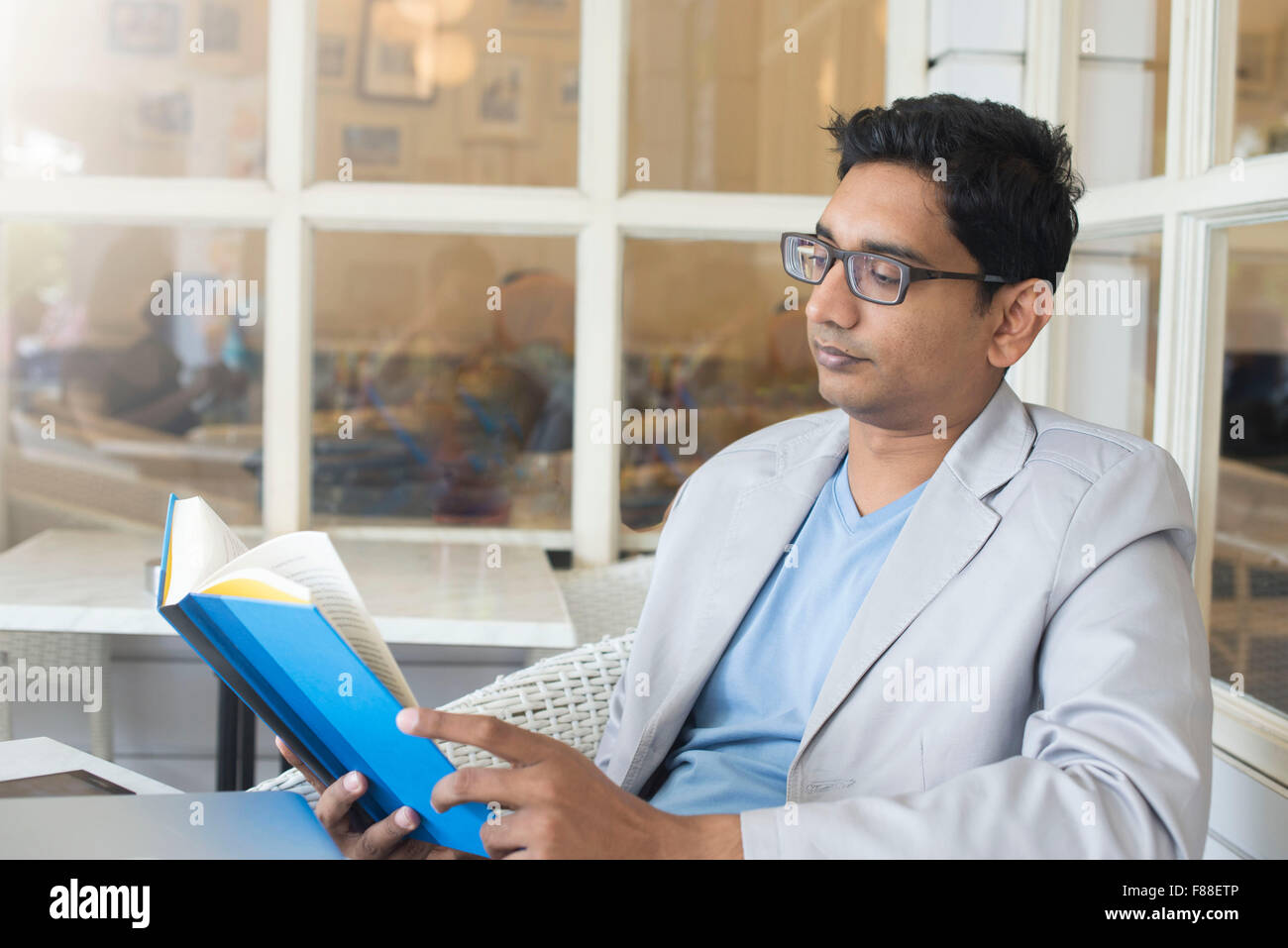 young indian male reading book on cafe Stock Photo - Alamy