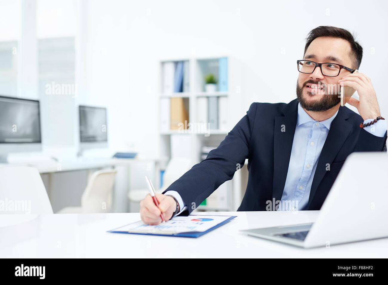 Handsome employer speaking on the phone in office Stock Photo - Alamy