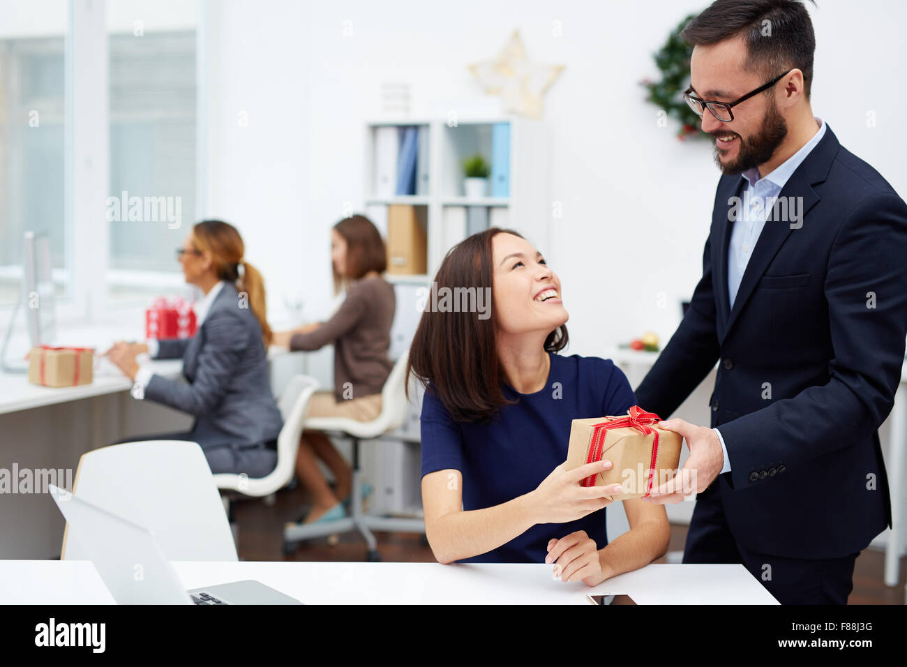 Handsome businessman making Christmas surprise to his secretary in ...