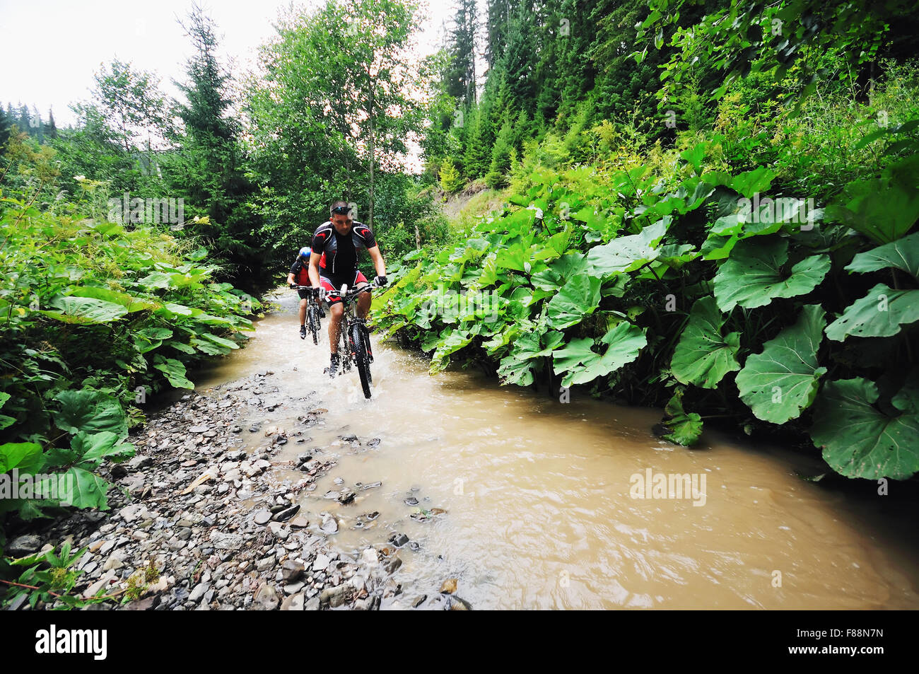 young man drive mountain bike over water river Stock Photo - Alamy