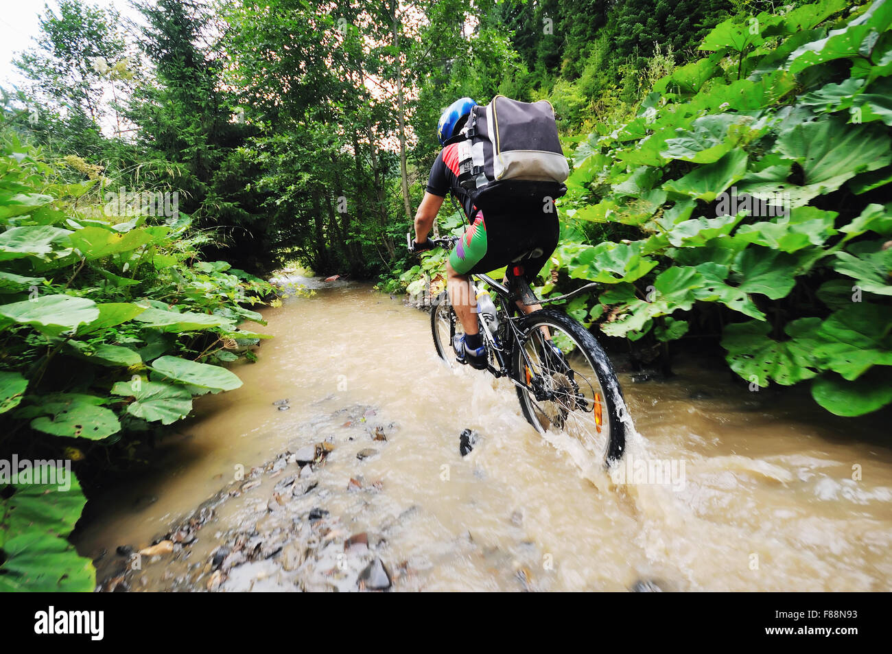 young man drive mountain bike over water river Stock Photo - Alamy