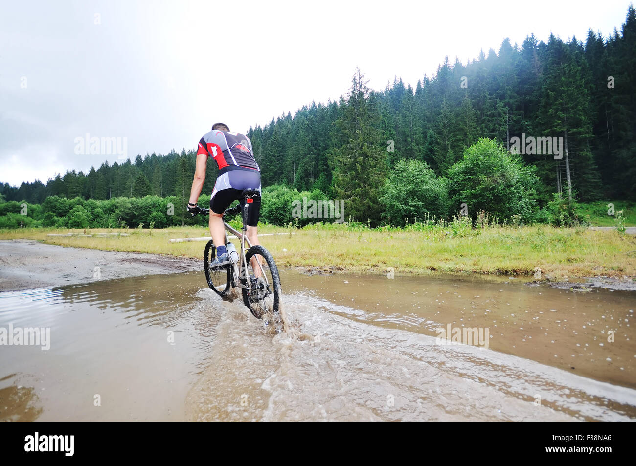 young man drive mountain bike over water river Stock Photo - Alamy