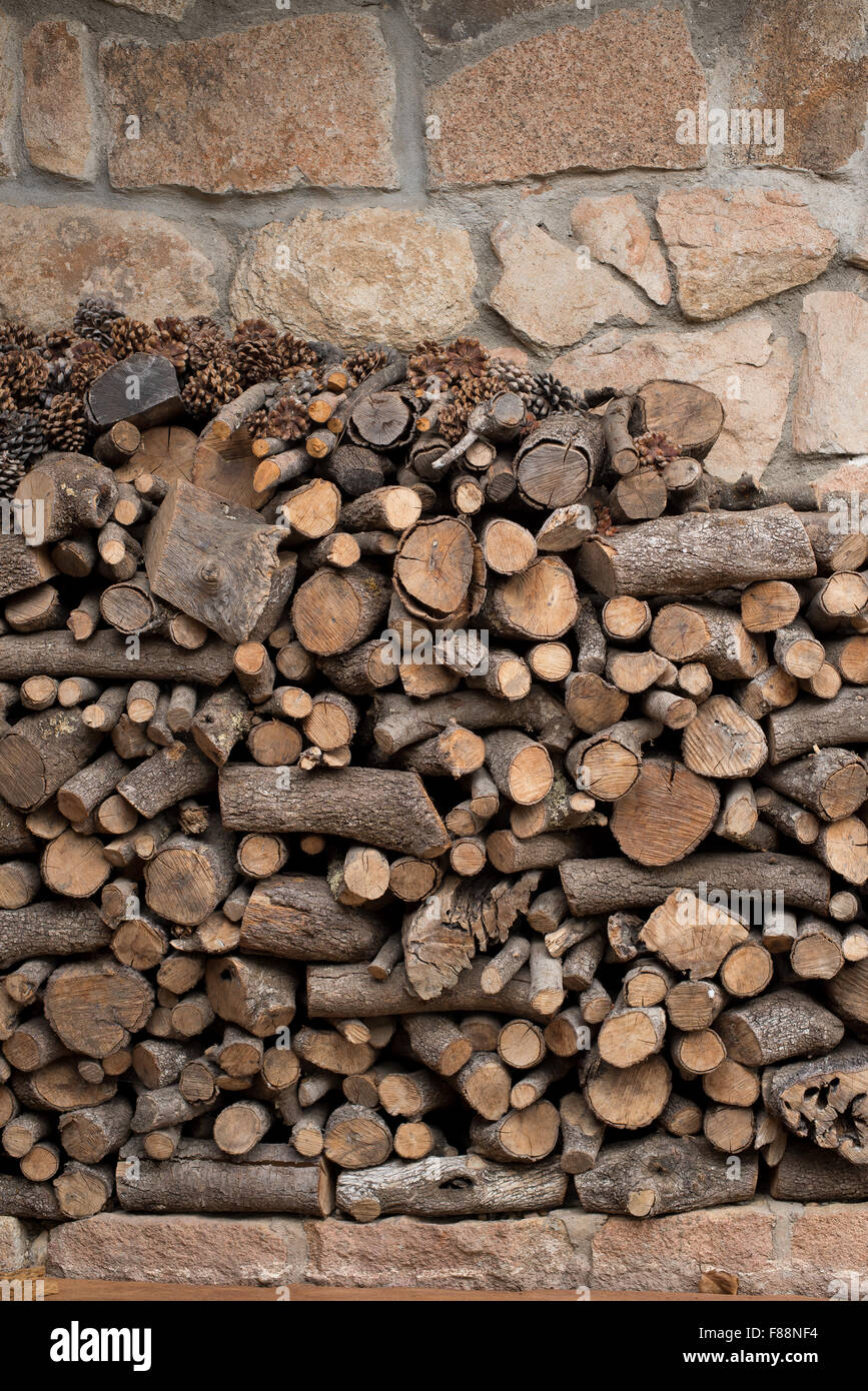 Big pile of logs front a stone wall Stock Photo - Alamy