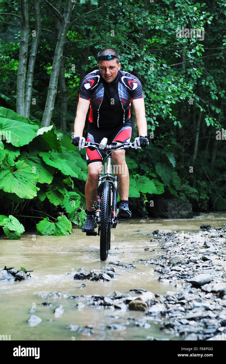 young man drive mountain bike over water river Stock Photo - Alamy