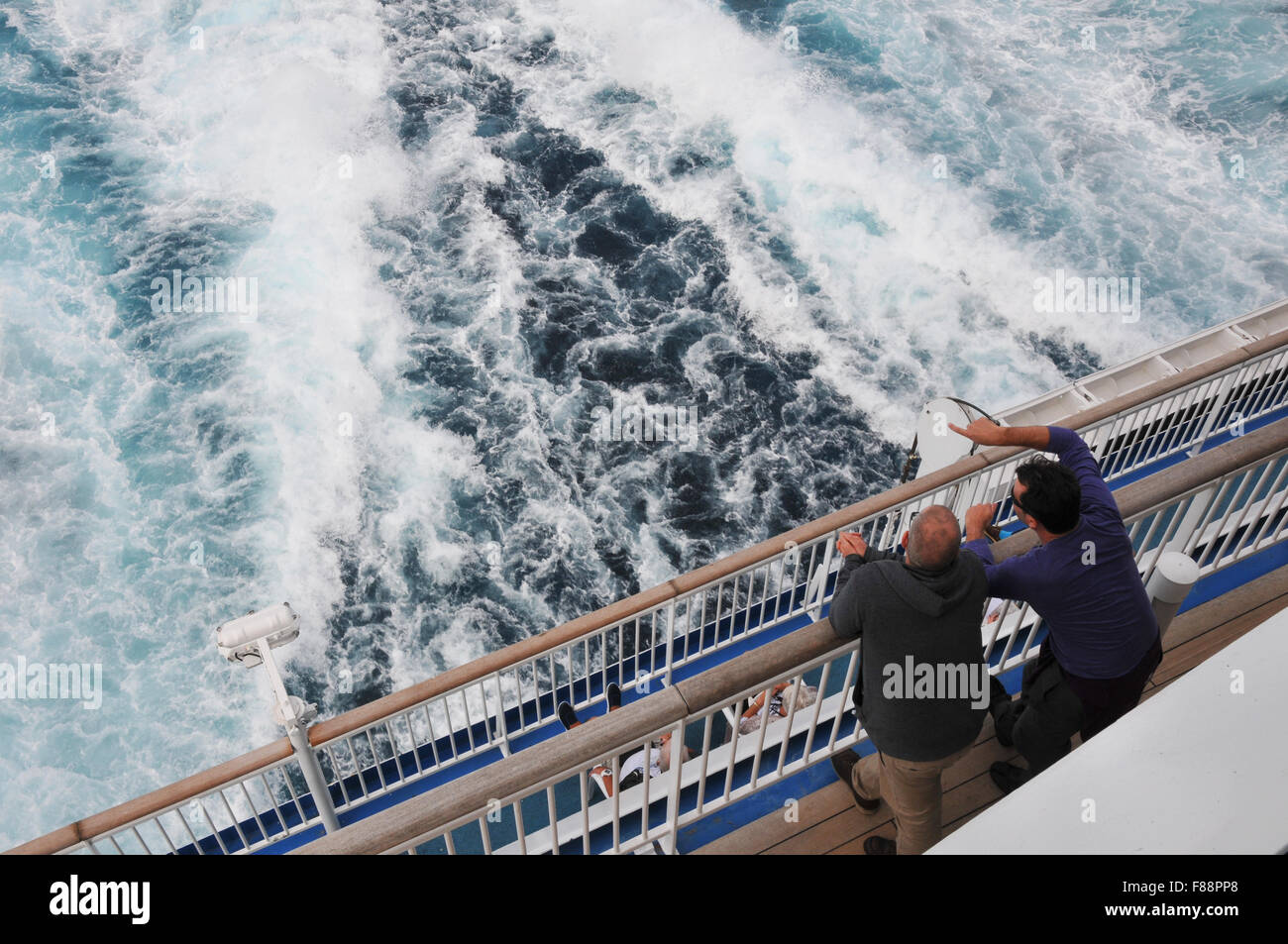 two men lean over rails and look out from ferry deck Stock Photo - Alamy