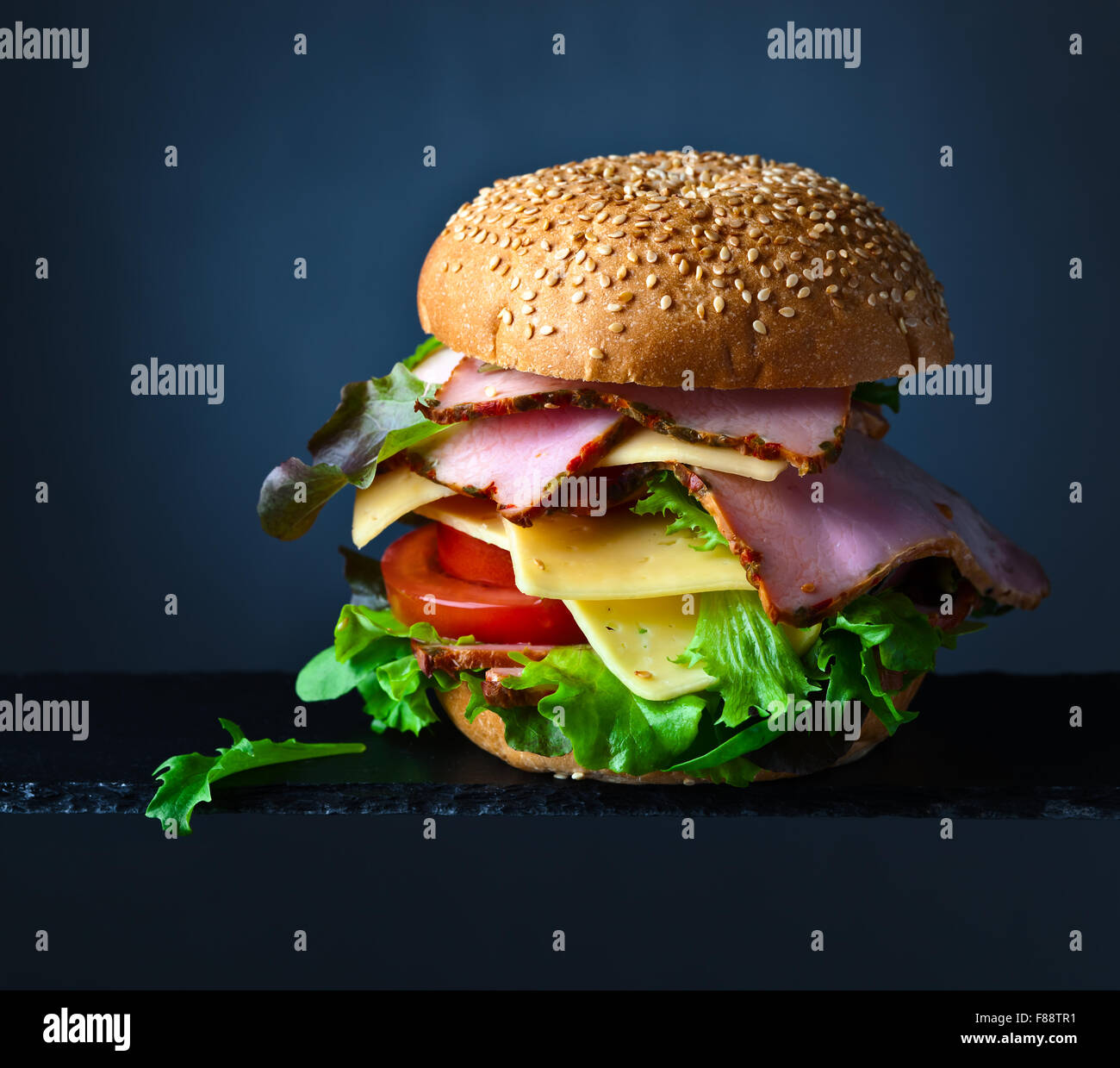 burger with ham and salad on a dark background Stock Photo - Alamy