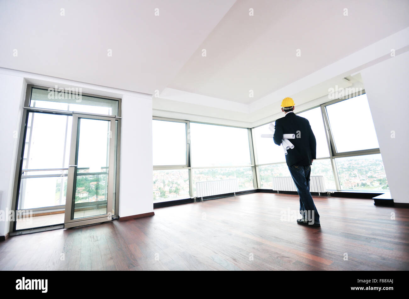 happy young architect portrait with helmet and blueprints indoor at new ...