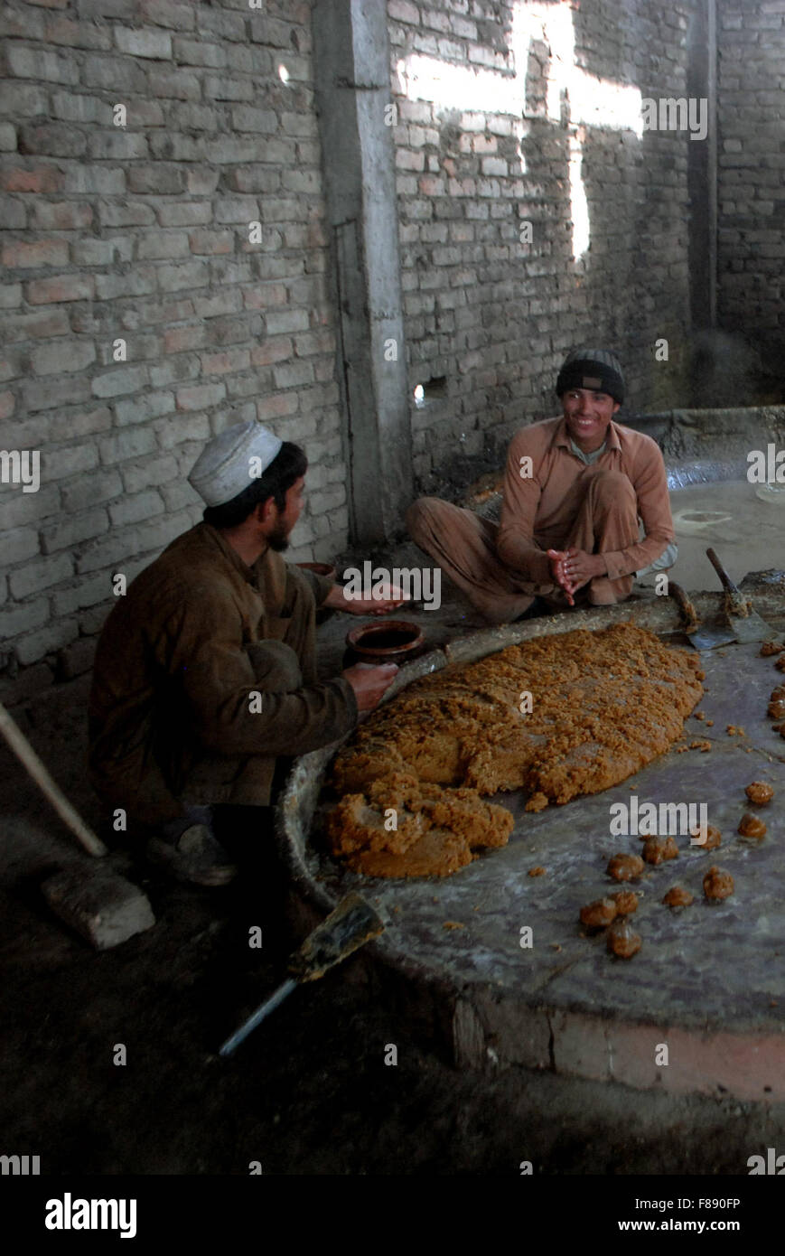 Peshawar. 7th Dec, 2015. People make sugar balls with sugarcane juice ...