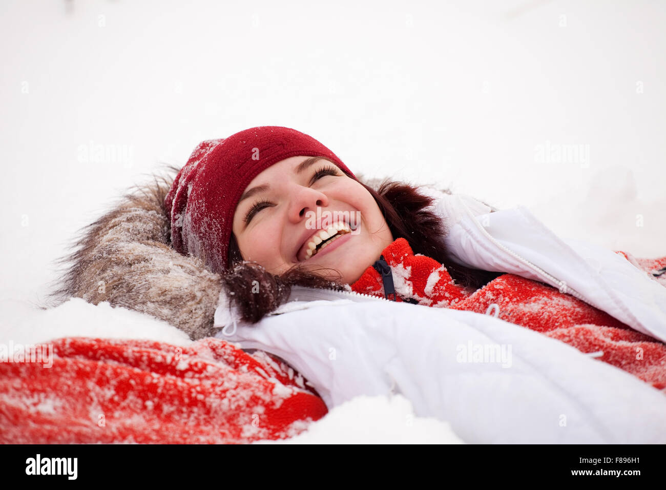 Happy girl lying down on the snow in winter Stock Photo - Alamy