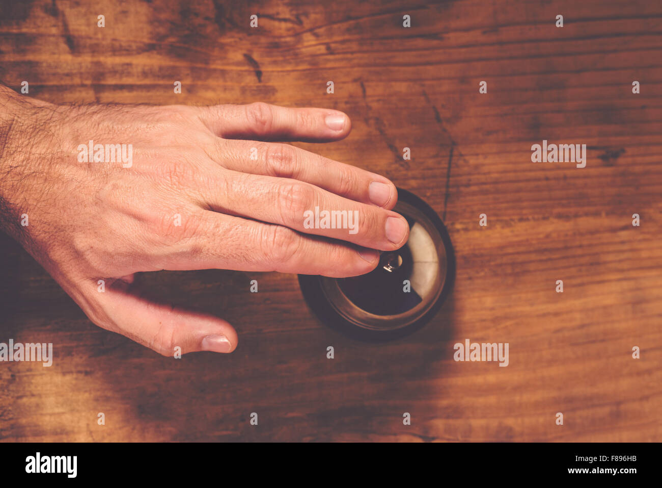 Man ringing hotel service bell on reception desk, retro toned image ...