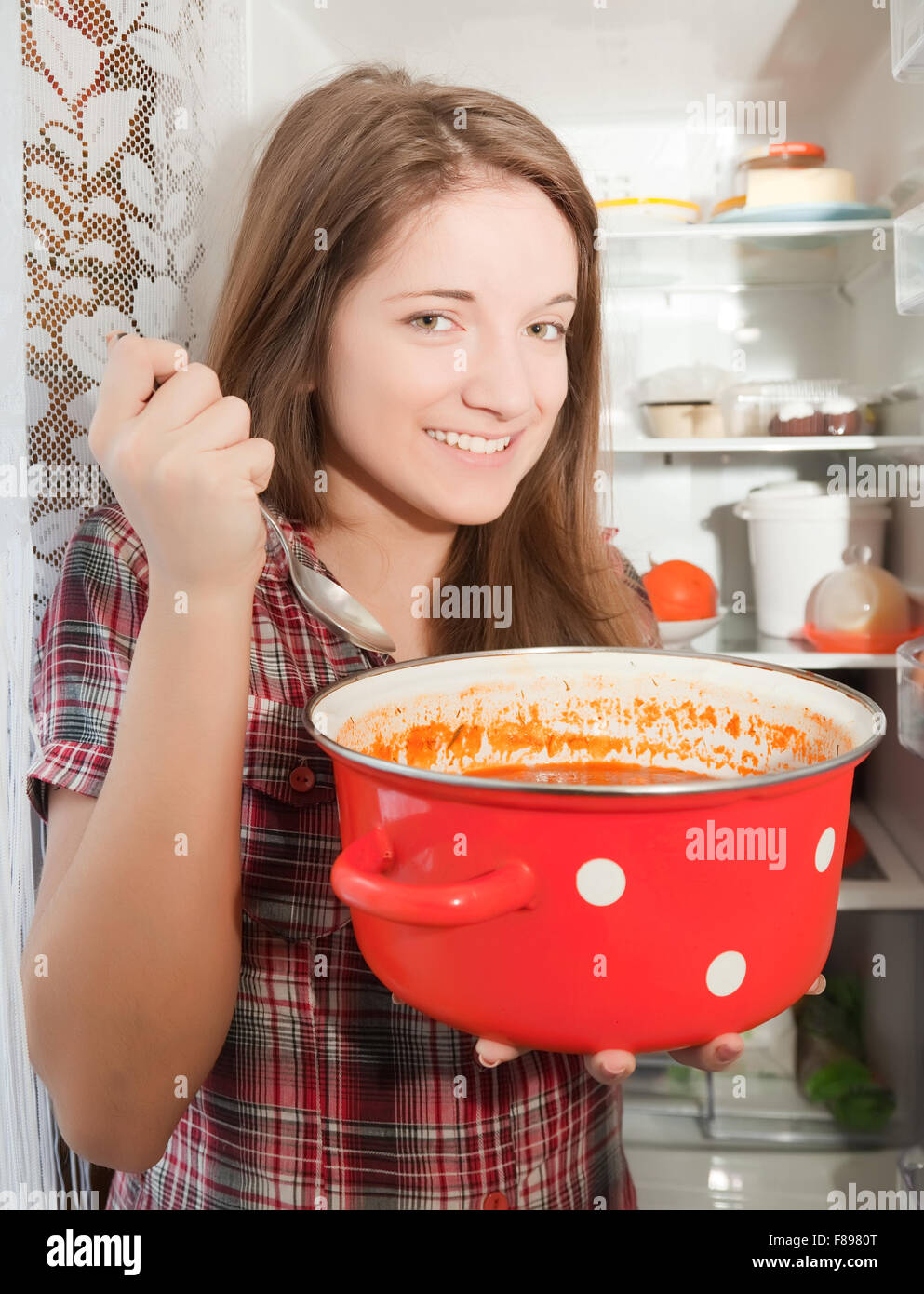 Teenager girl eating soup from pan near fridge at home Stock Photo - Alamy