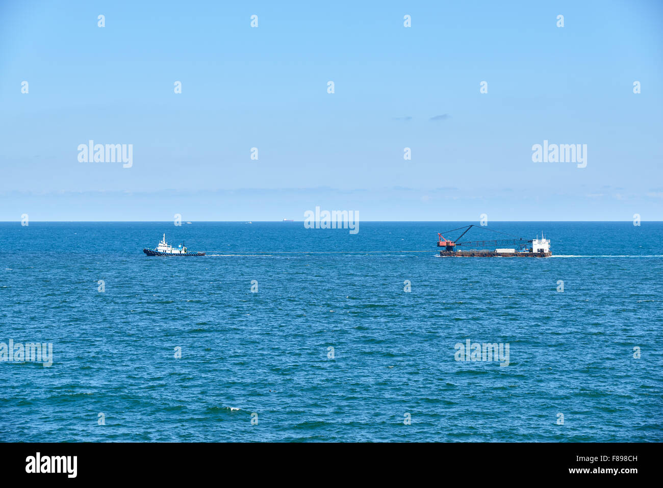 Tug towing a floating crane at a sea Stock Photo - Alamy