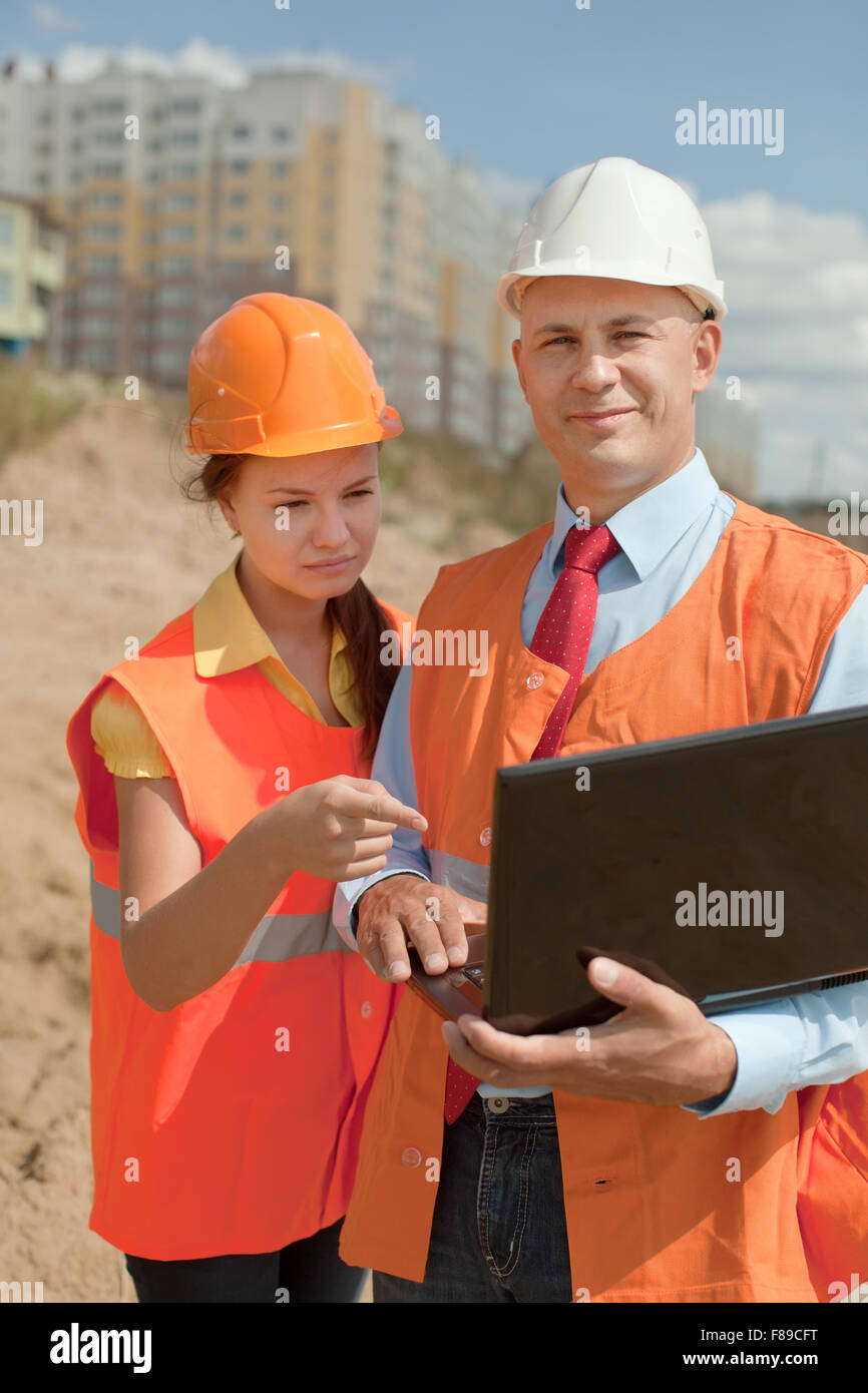 Two architects wearing protective helmet works in front of building ...
