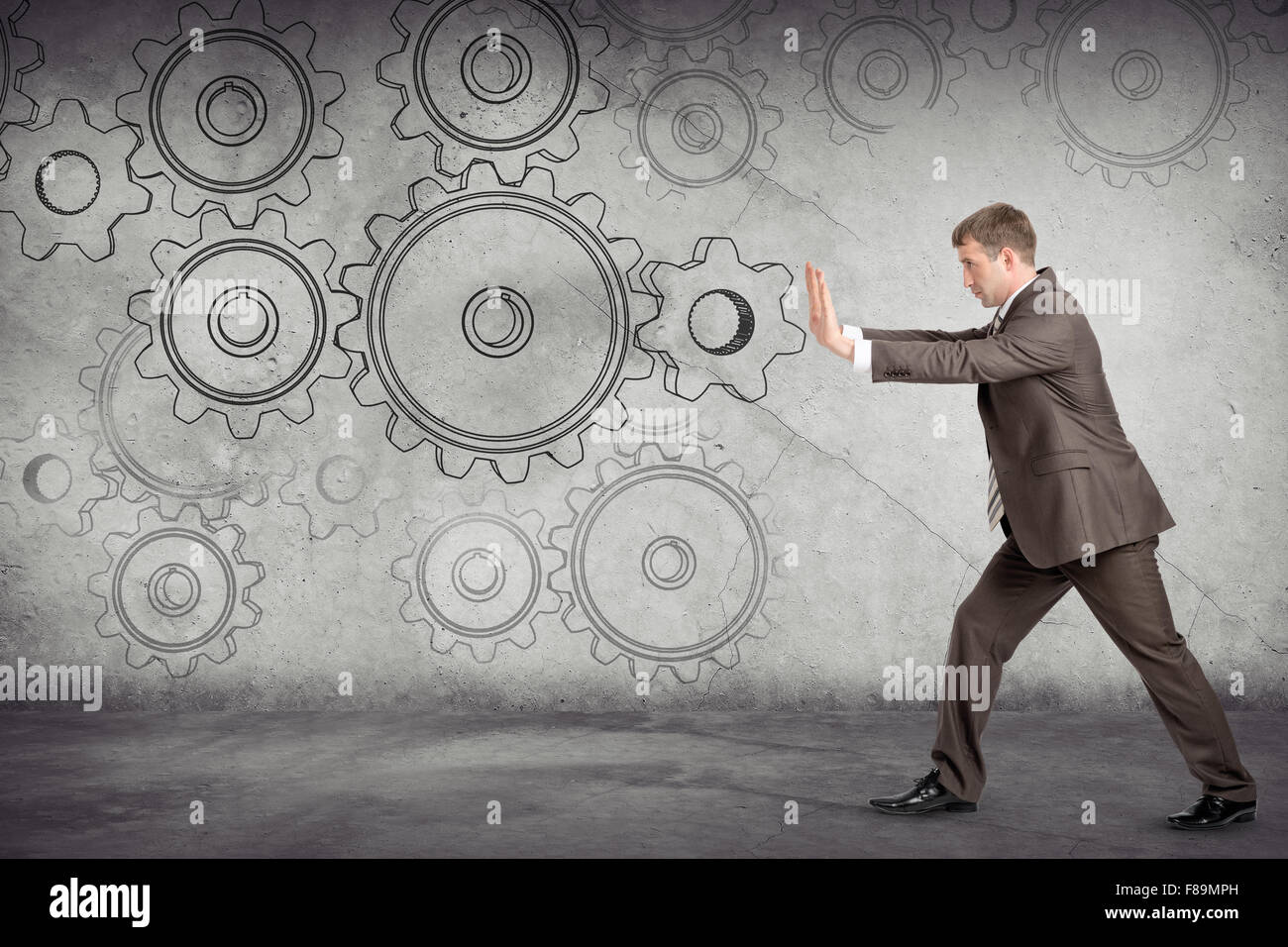 Businessman pushing cog wheel Stock Photo - Alamy