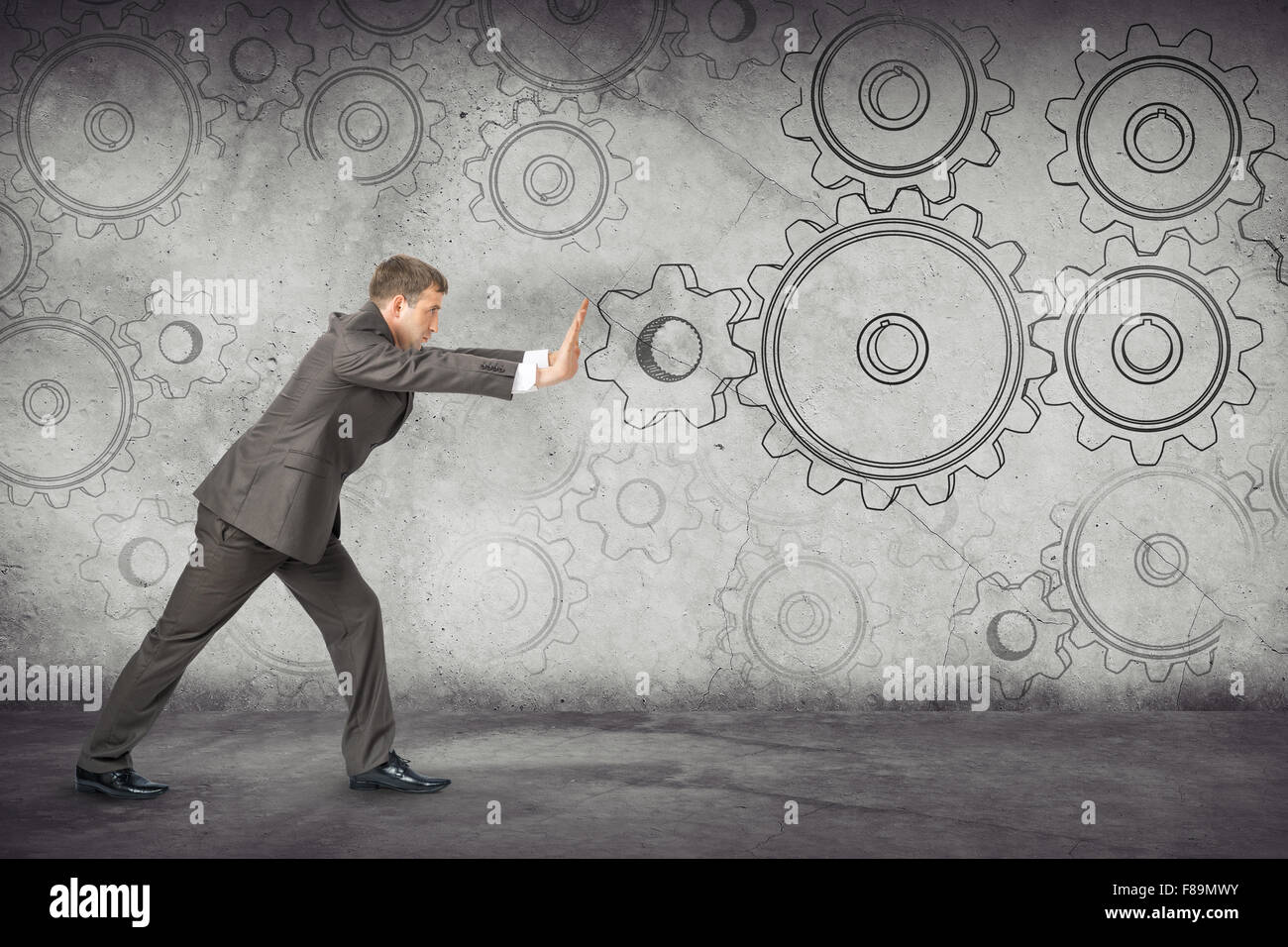 Businessman pushing cog wheels Stock Photo - Alamy
