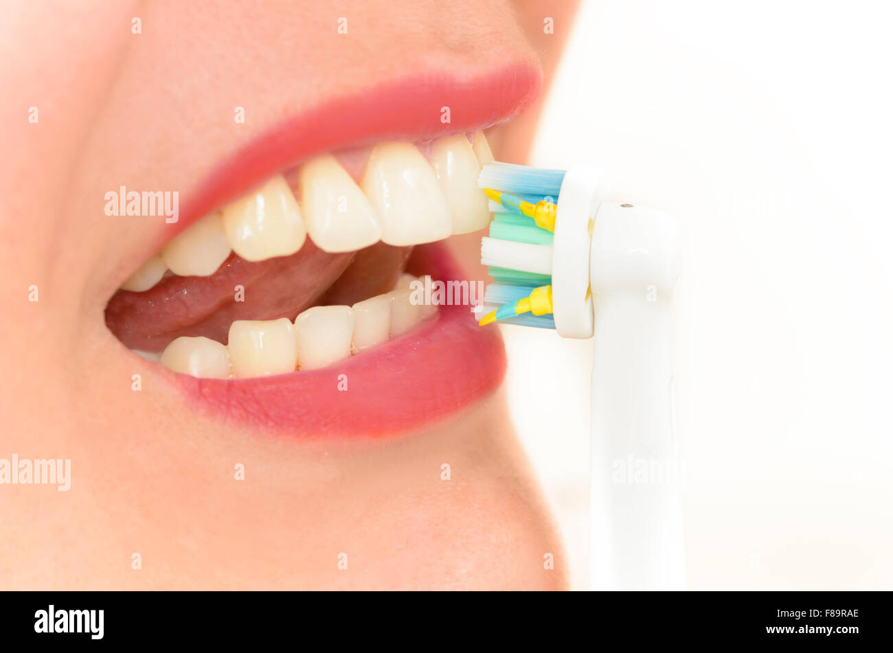 Young woman using electric toothbrush looking in the mirror Stock Photo ...