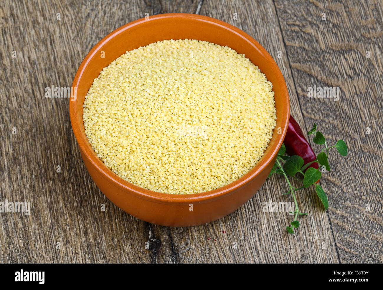 Raw couscous with pepper and herbs on the wood background ready for ...