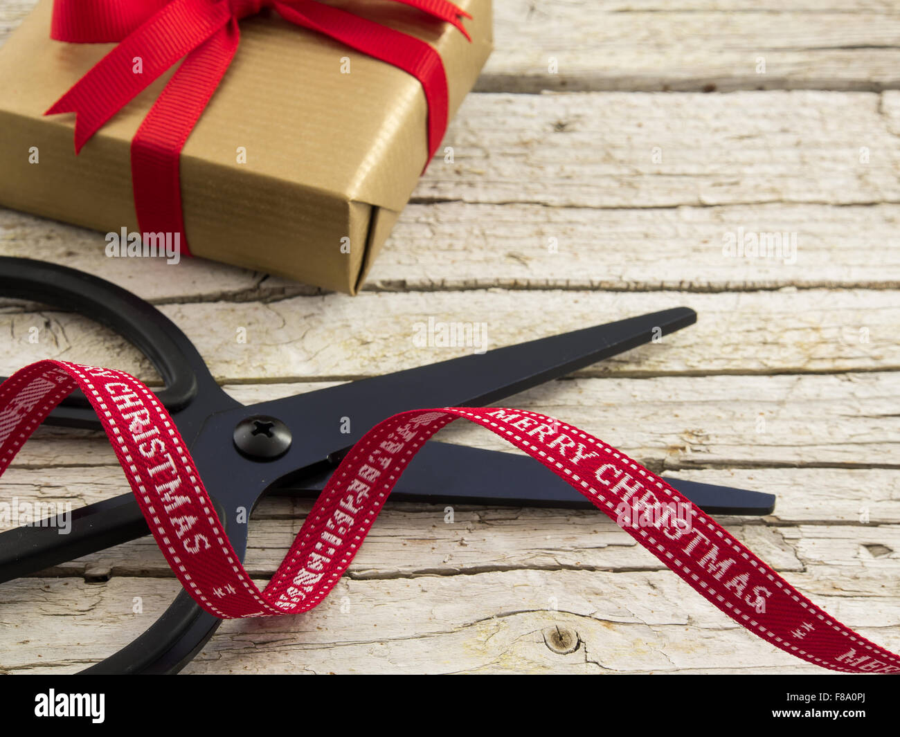 detail of retro black scissor, gift and red ribbon on wooden background ...