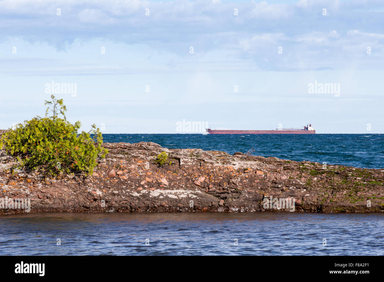 Great Lakes oar boat on the horizon of Lake Superior passing behind a ...