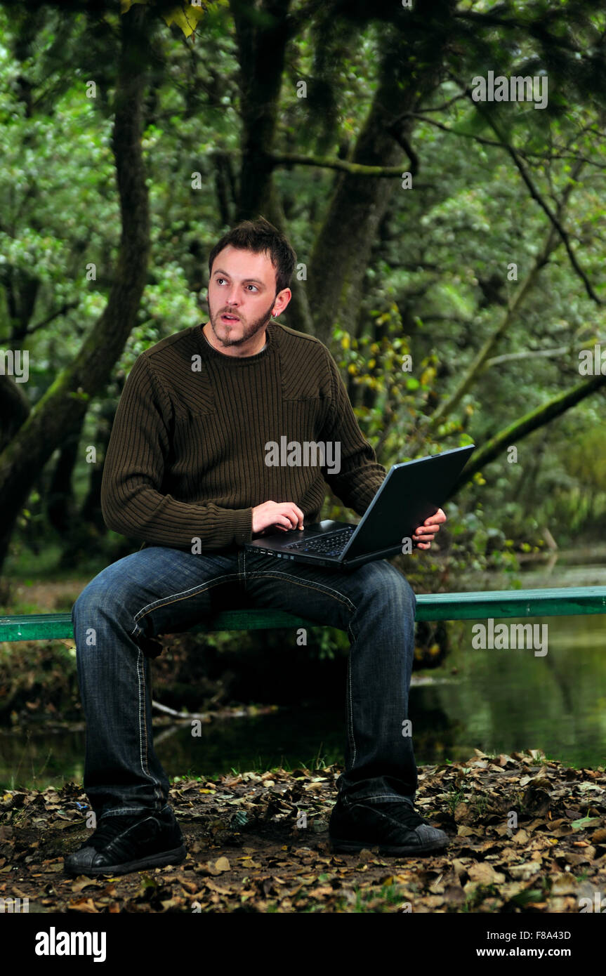 one young businessman working on laptop outdoor with green nature in ...