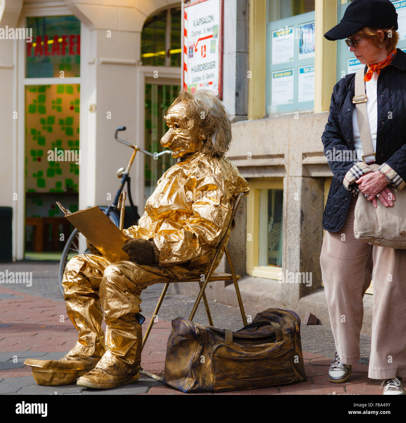 Golden man reading newspaper in Amsterdam and American Tourist watching ...