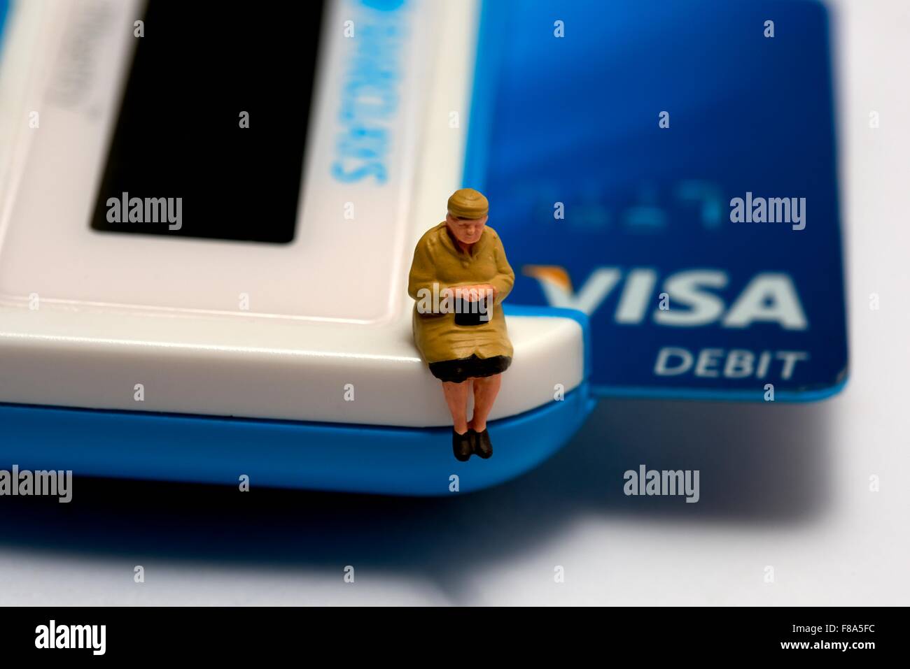 A Miniature pensioner figures sitting on a pin sentry machine with a ...