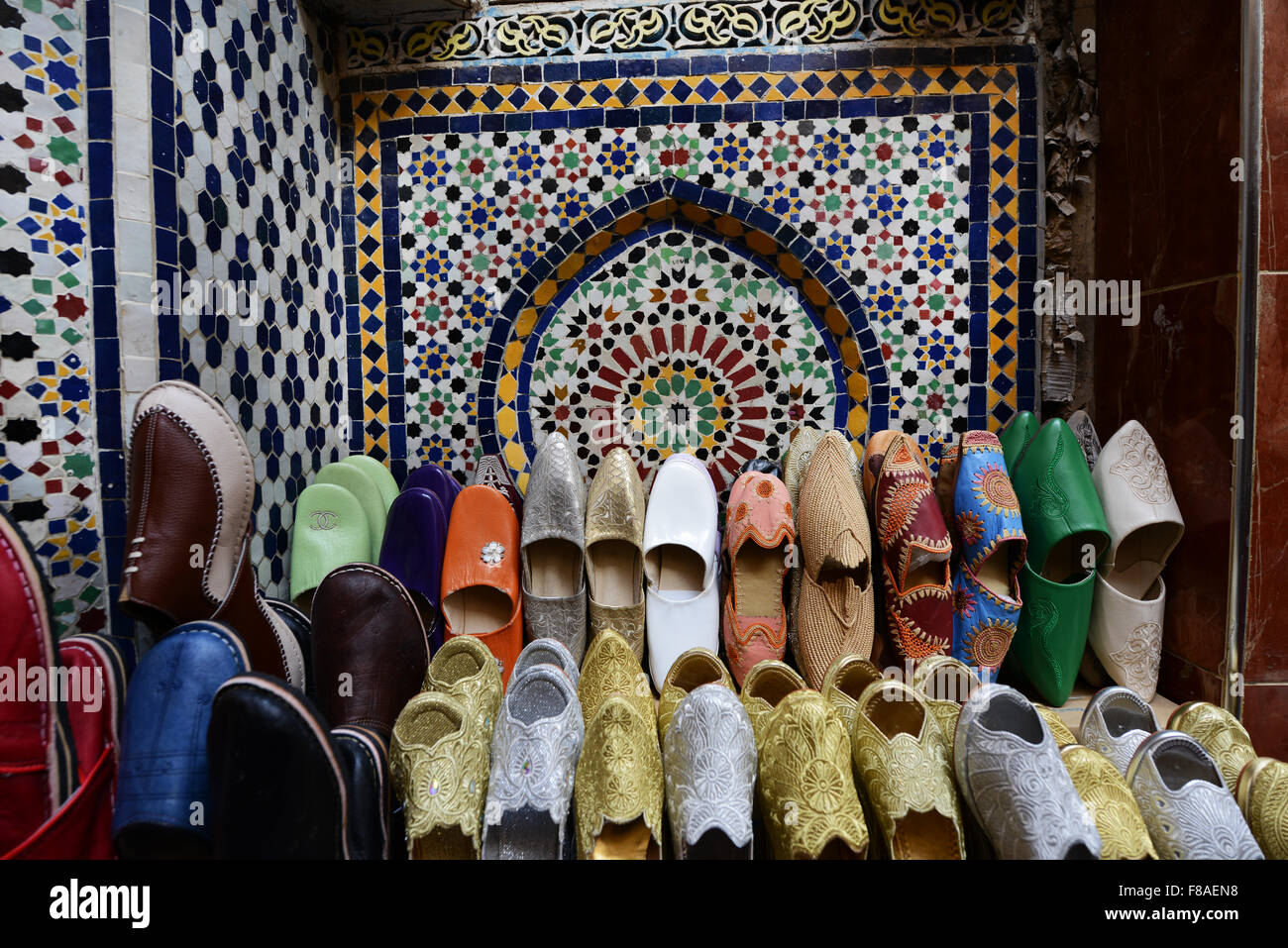 Traditional Moroccan shoes displayed by a colorful zellige wall and ...
