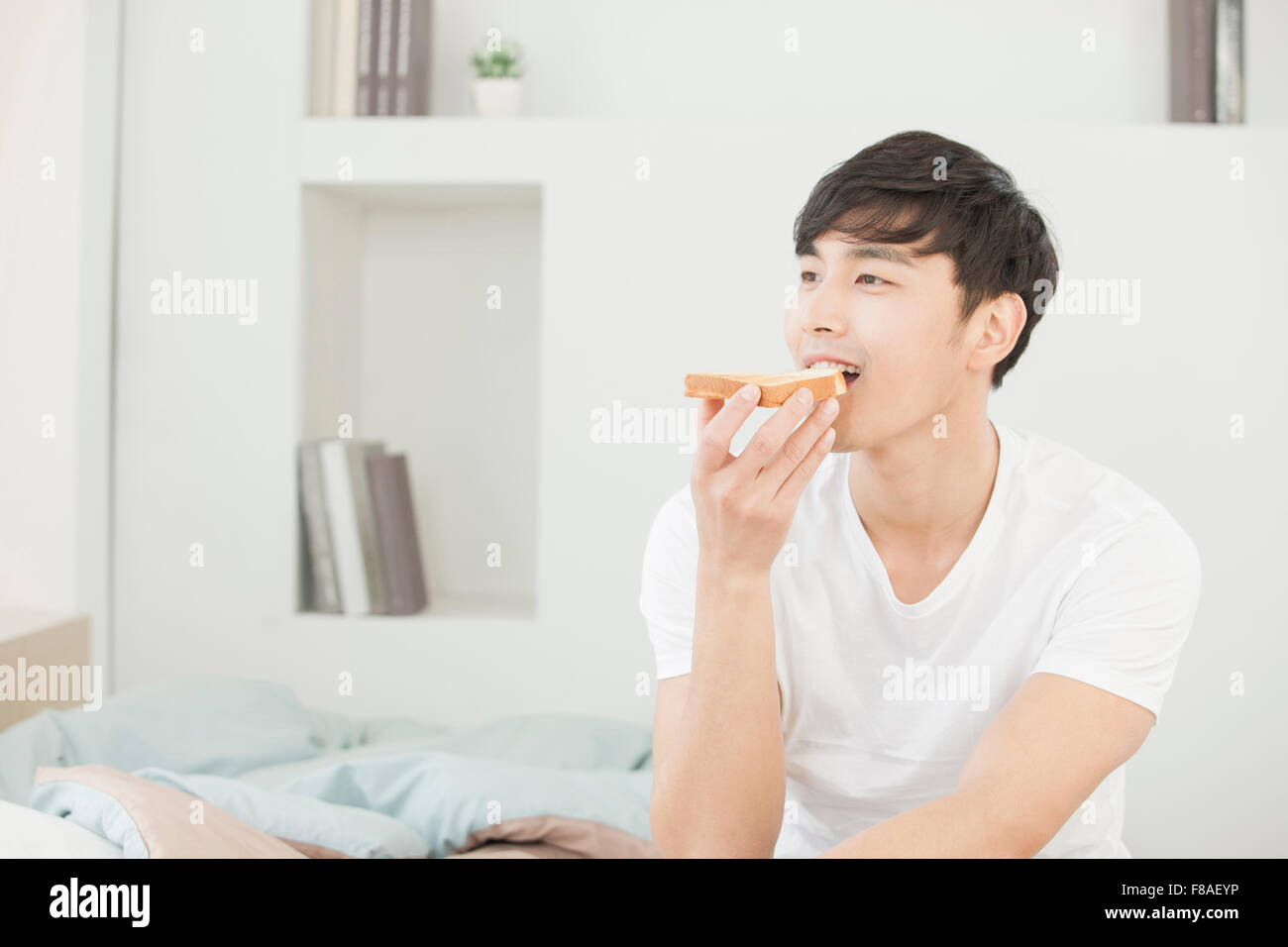 Asian man biting a piece of bread Stock Photo - Alamy