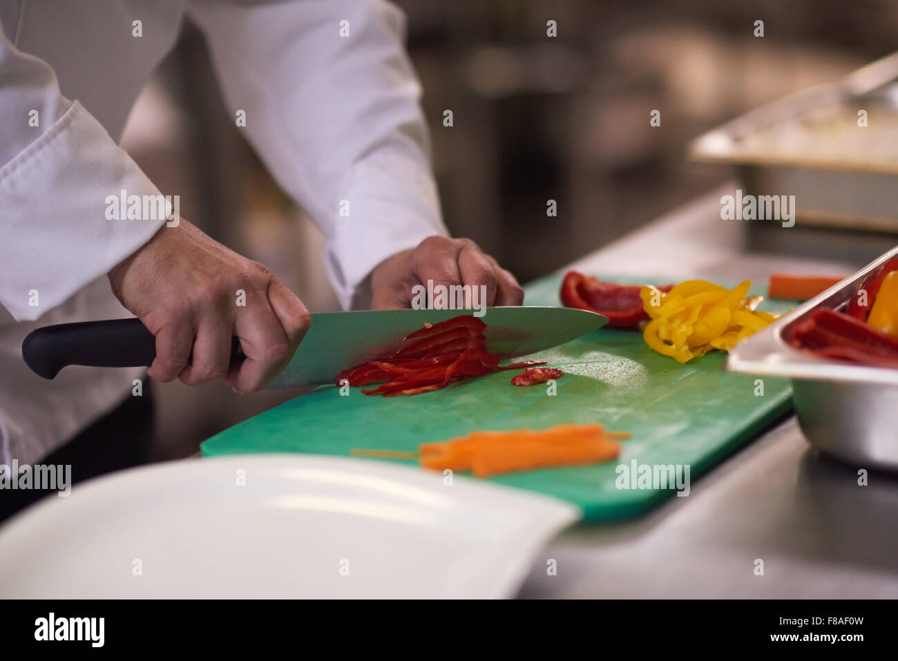 chef in hotel kitchen slice vegetables with knife and prepare food ...