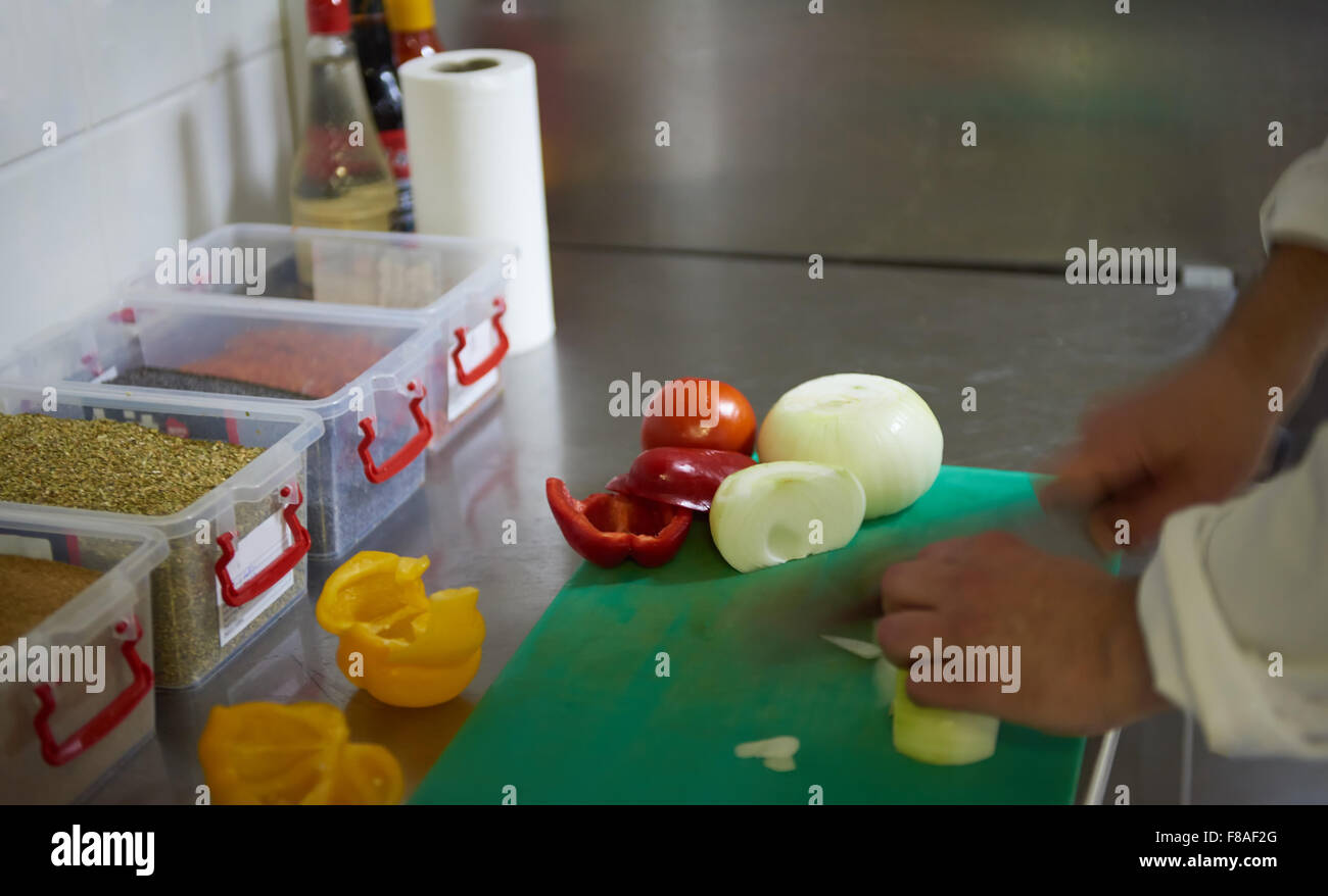 chef in hotel kitchen slice vegetables with knife and prepare food ...