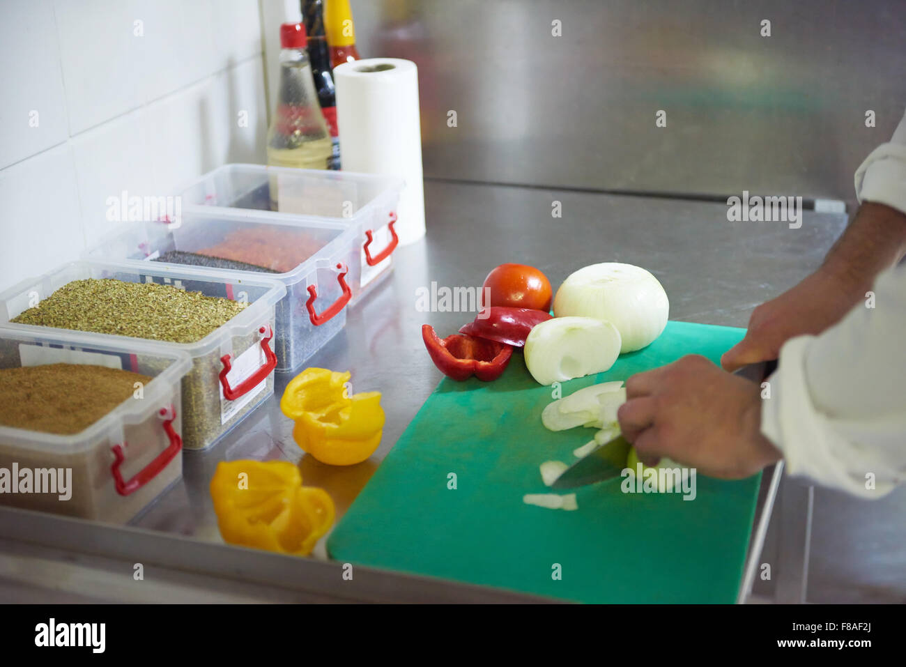 chef in hotel kitchen slice vegetables with knife and prepare food ...