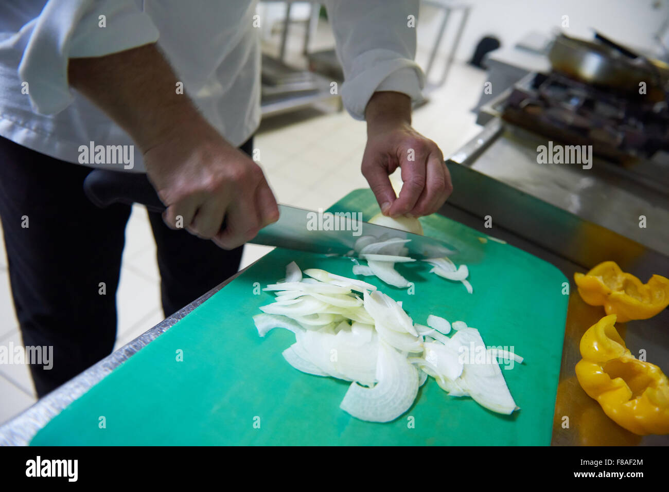 chef in hotel kitchen slice vegetables with knife and prepare food ...