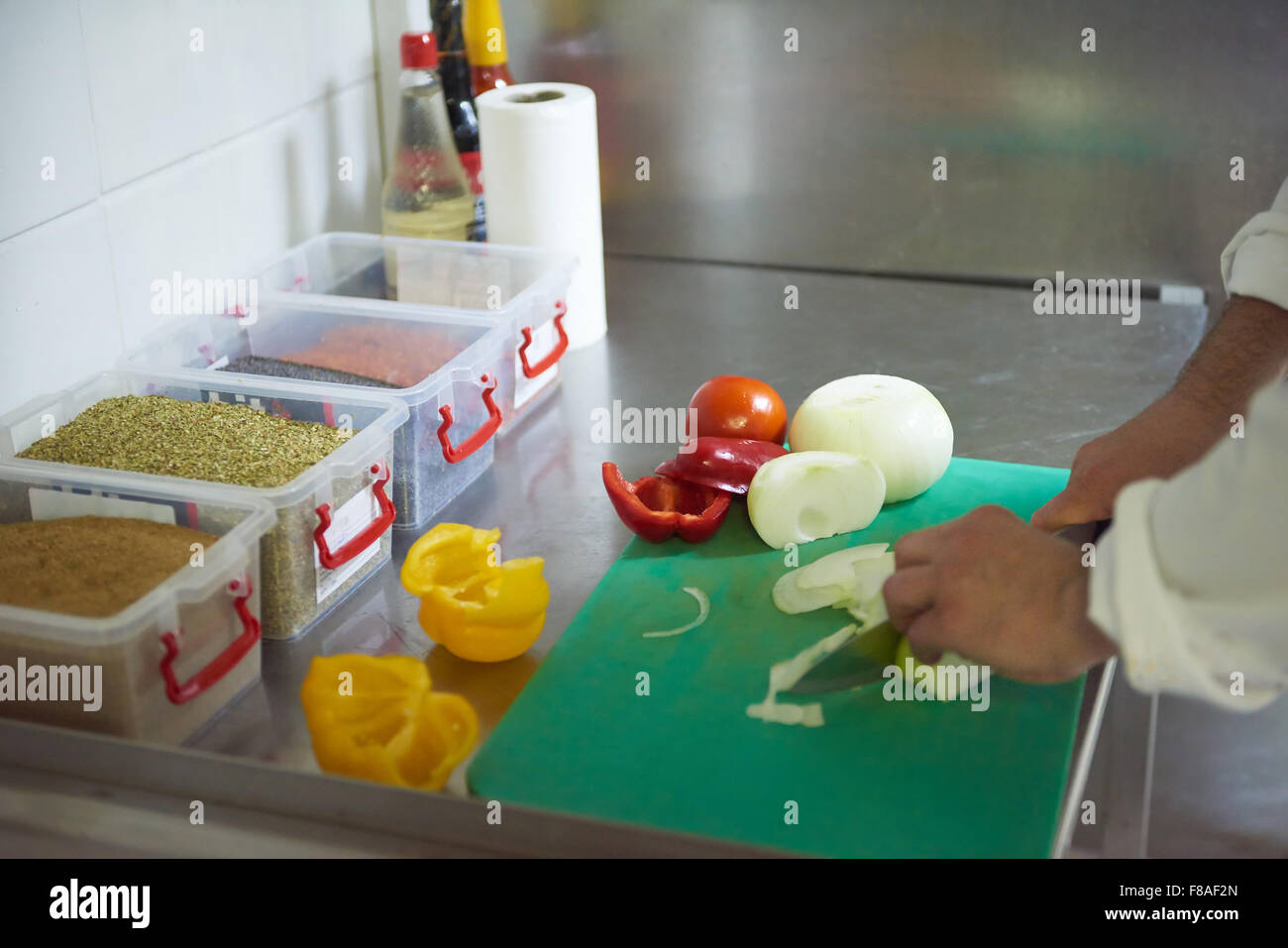 chef in hotel kitchen slice vegetables with knife and prepare food ...