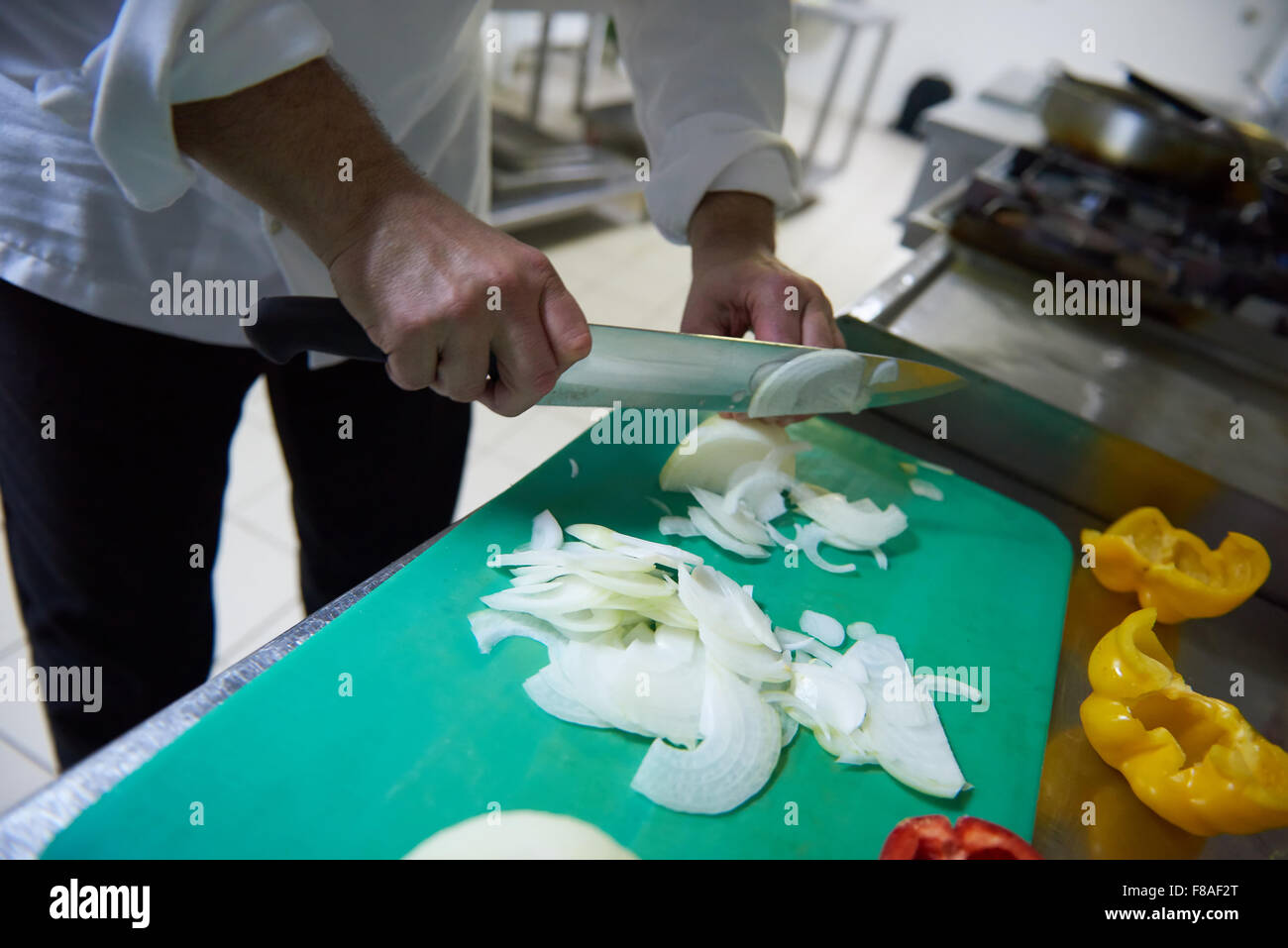 chef in hotel kitchen slice vegetables with knife and prepare food ...