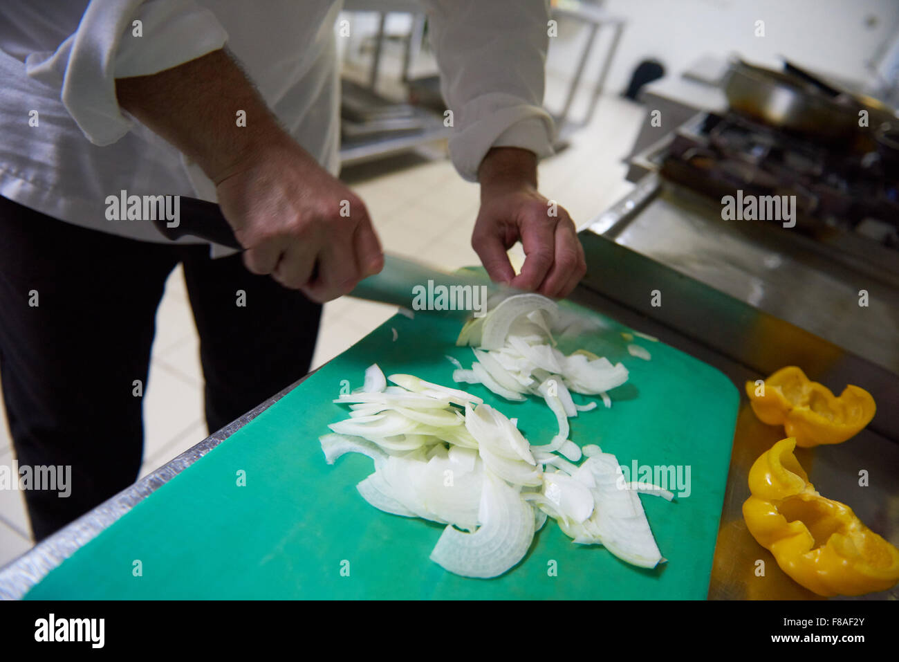chef in hotel kitchen slice vegetables with knife and prepare food ...