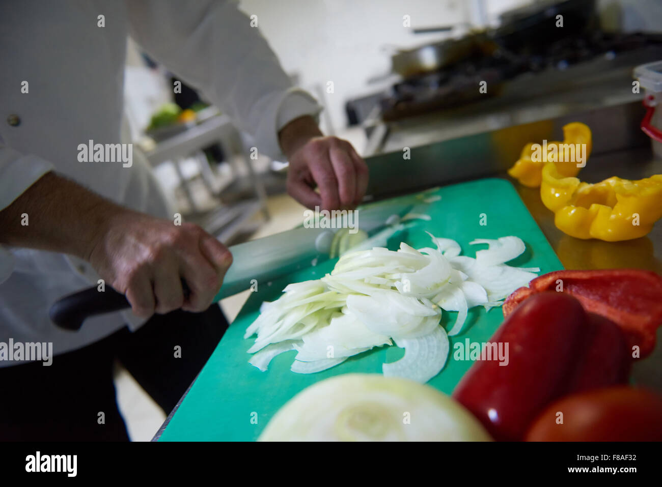 chef in hotel kitchen slice vegetables with knife and prepare food ...
