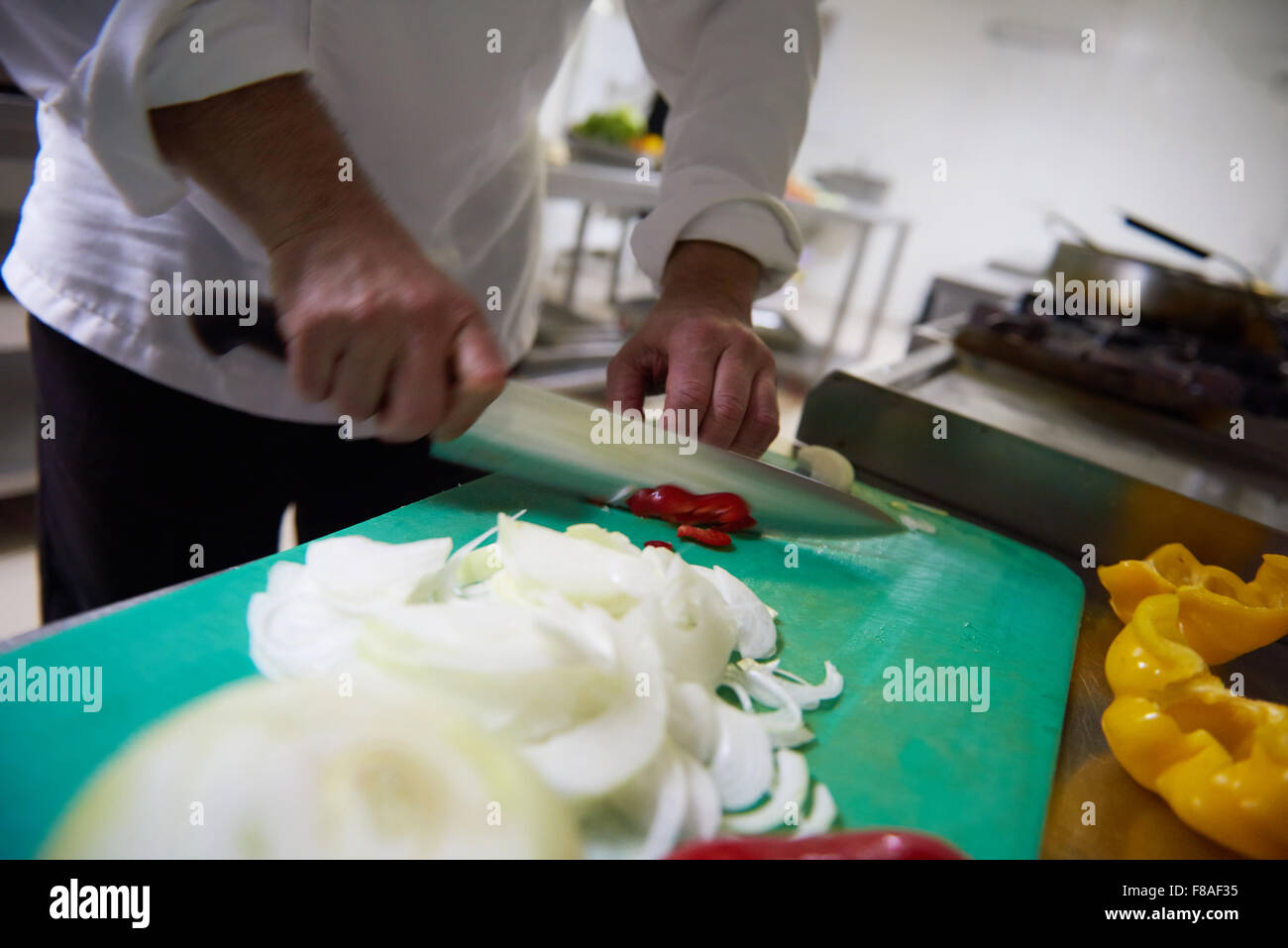 chef in hotel kitchen slice vegetables with knife and prepare food ...