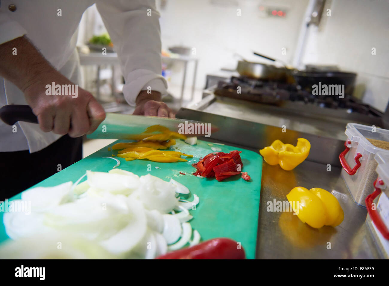 chef in hotel kitchen slice vegetables with knife and prepare food ...