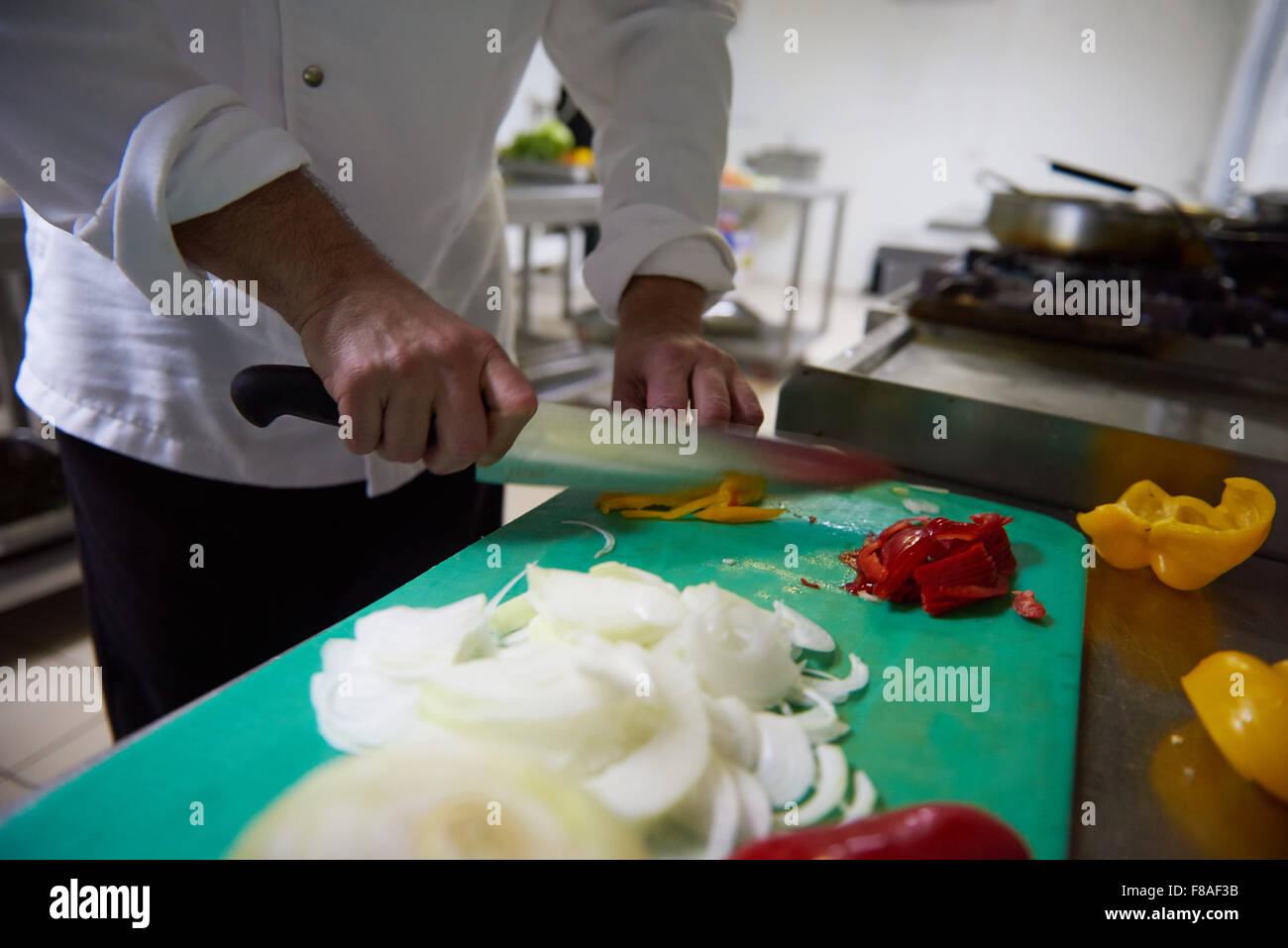 chef in hotel kitchen slice vegetables with knife and prepare food ...