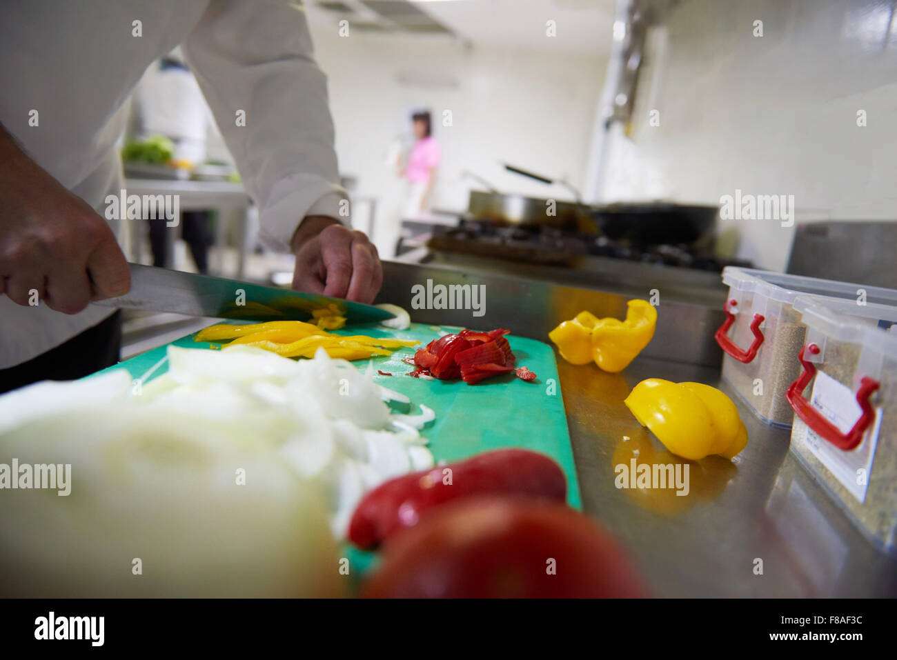 chef in hotel kitchen slice vegetables with knife and prepare food ...